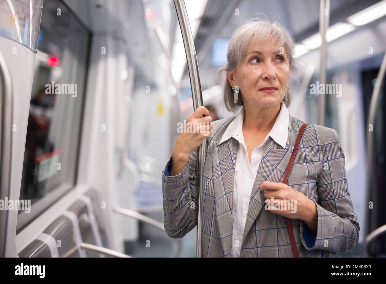 Senior lady standing in metro train Stock Photo - Alamy
