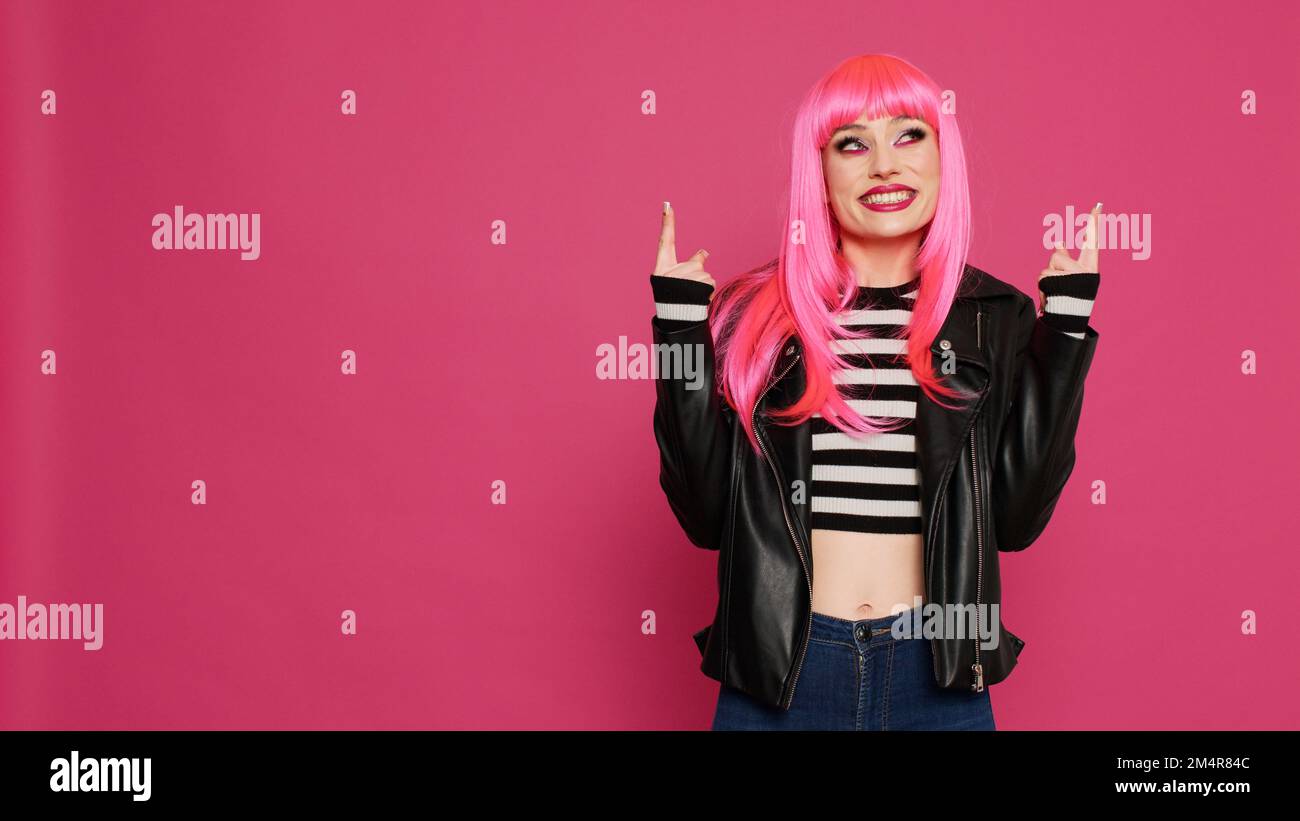 Stylish happy woman pointing up with fingers in studio, indicating ...