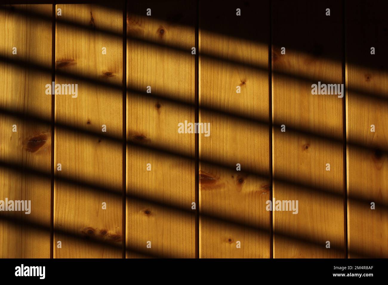 Jalousie casting dark diagonal shadows on warmly colored golden ...