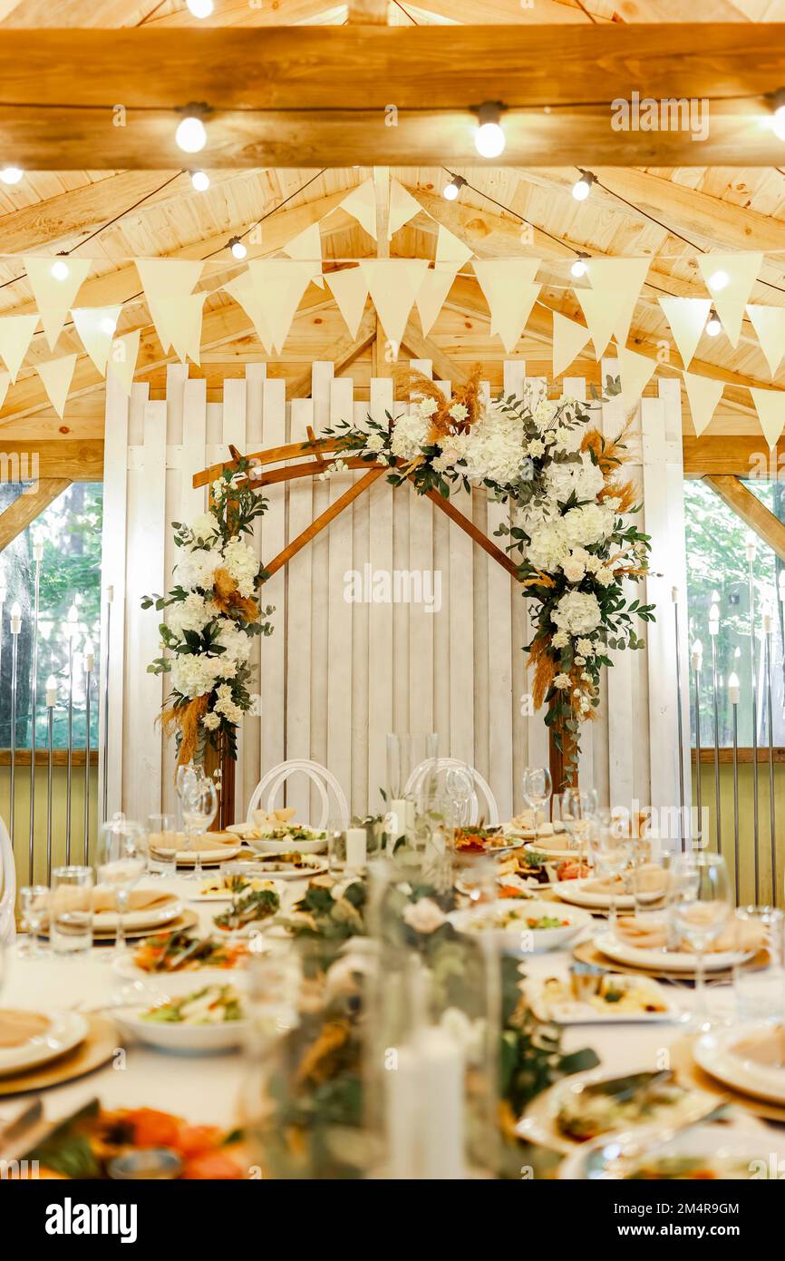Festive setting table with meals for wedding, wooden arch, stands ...