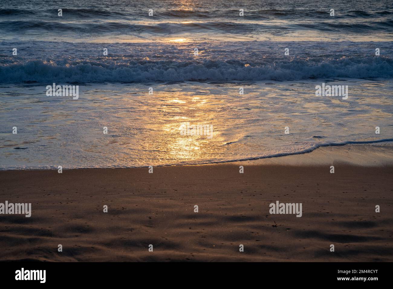 Sunset, sunlight reflected in the outgoing waves on the beach Stock ...