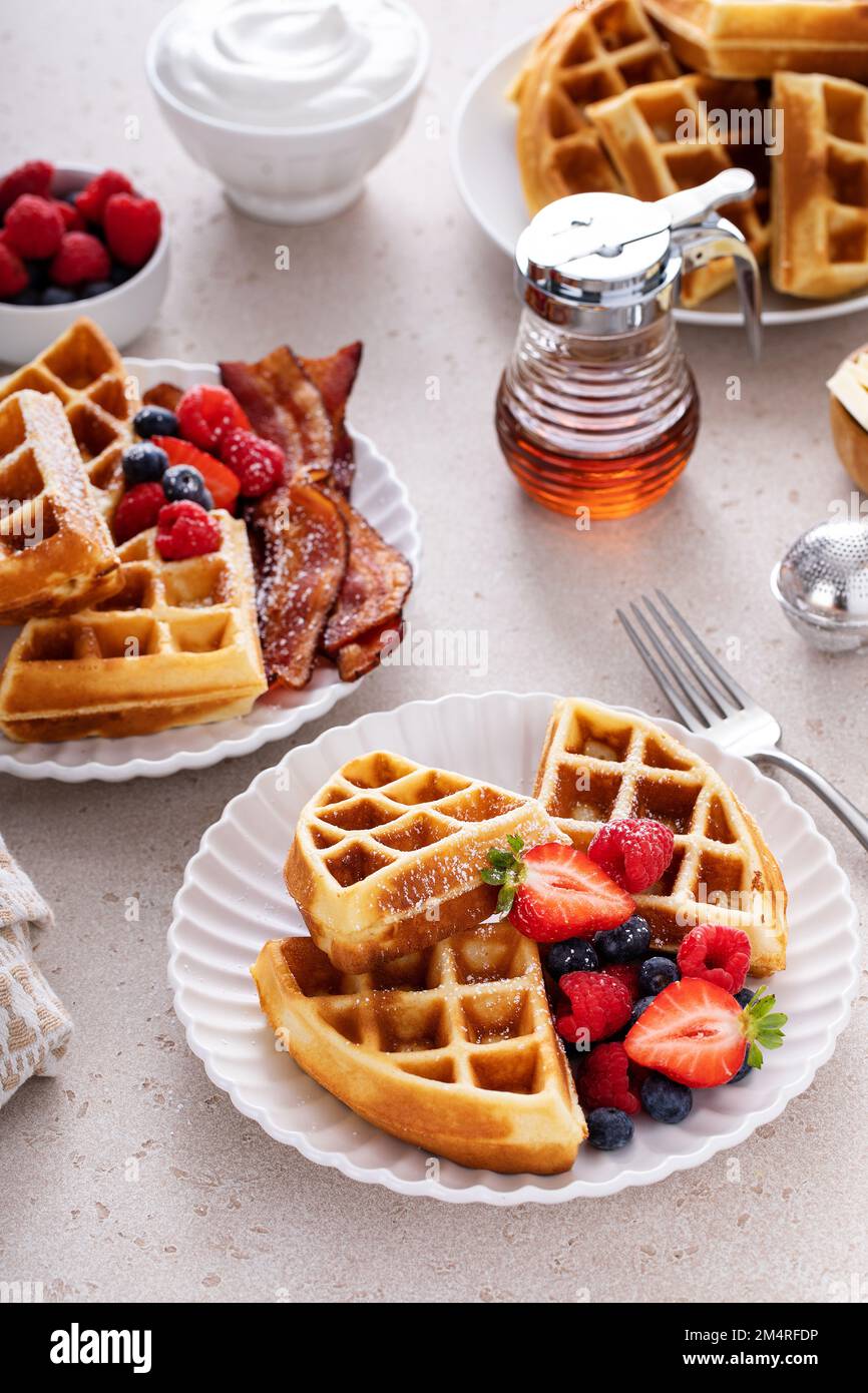 Breakfast table with waffles, berries and bacon Stock Photo - Alamy