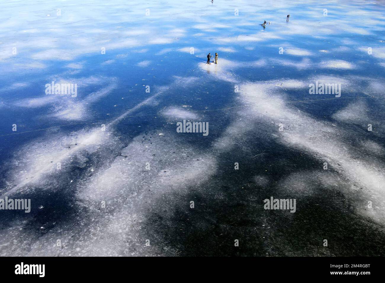 icy background in winter. Fishermen are fishing on beautiful blue ice ...