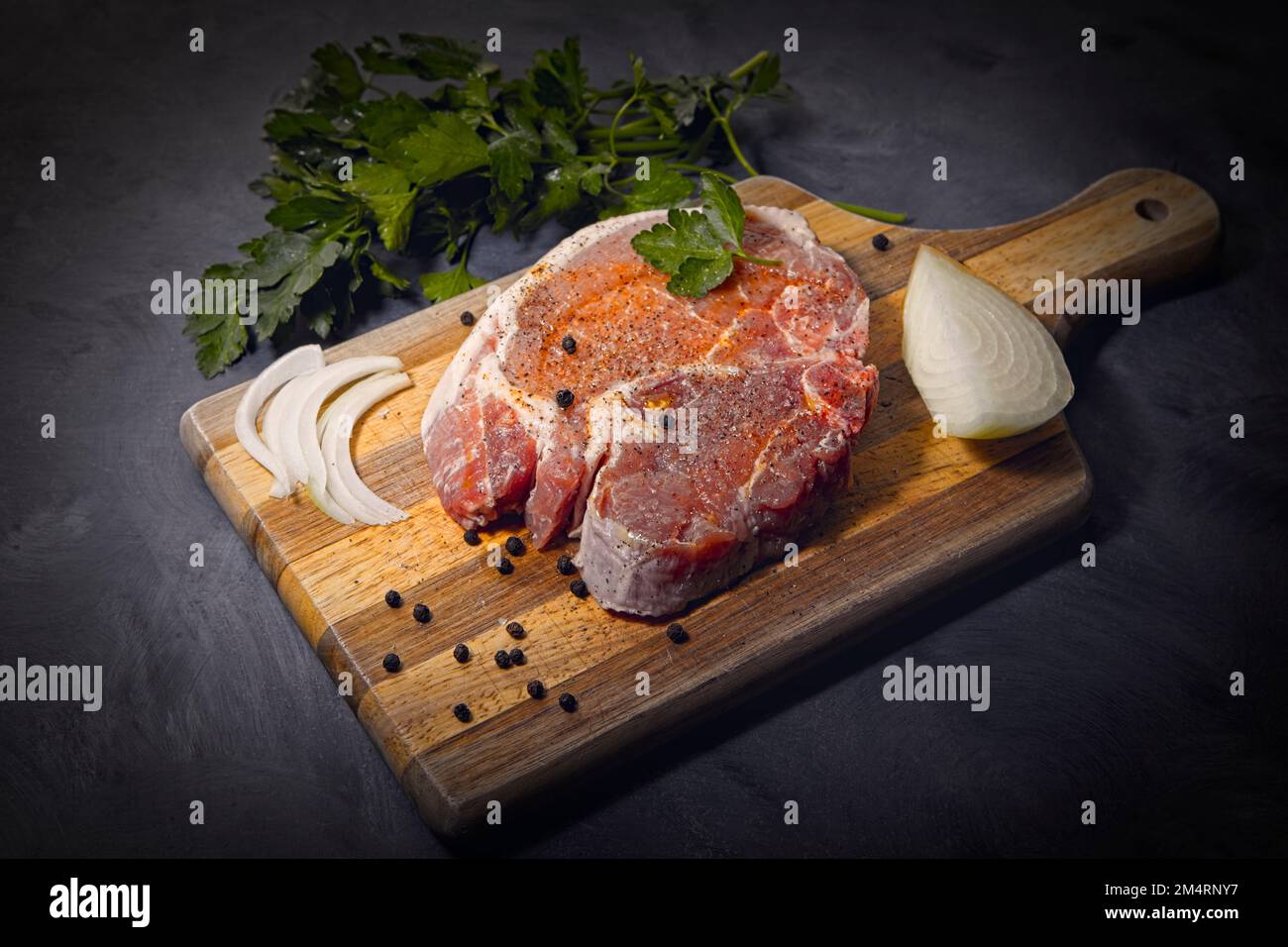 An overview of a raw pork chop cutlet on a wooden cutting board with ...