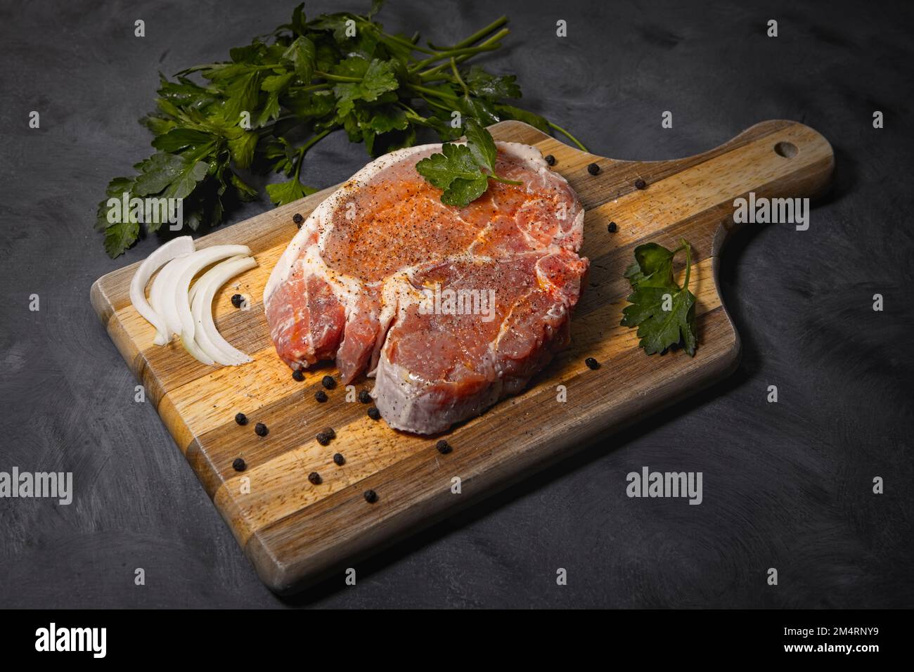 An overview of a raw pork chop cutlet on a wooden cutting board with ...