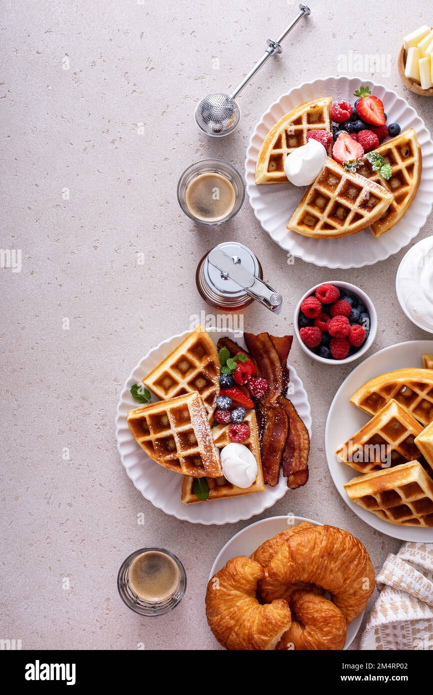 Breakfast table with waffles, croissants, sausage and bacon served with ...
