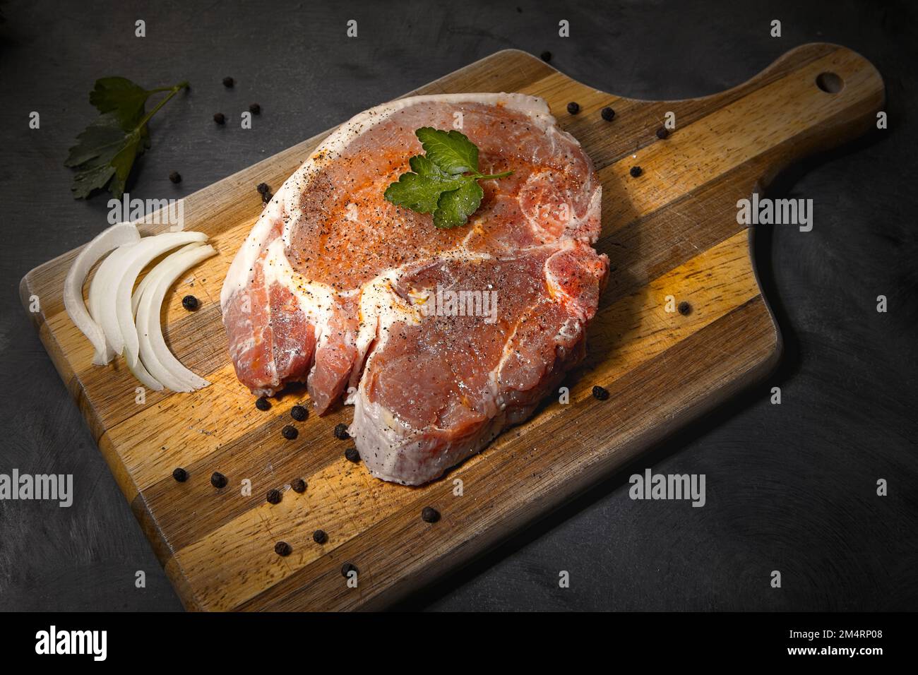 An overview of a raw pork chop cutlet on a wooden cutting board with ...