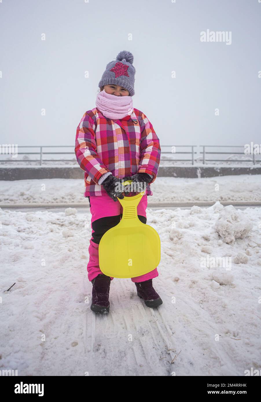Little girl with a yellow snow shovel Stock Photo - Alamy