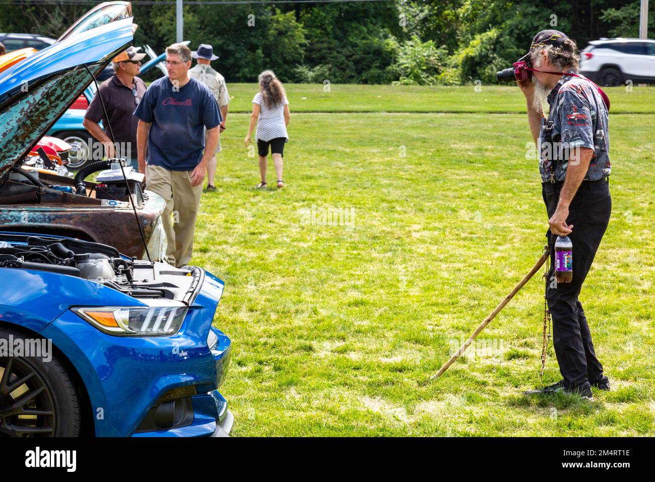 A blue late model Ford Mustang in line with cars being photographed at ...