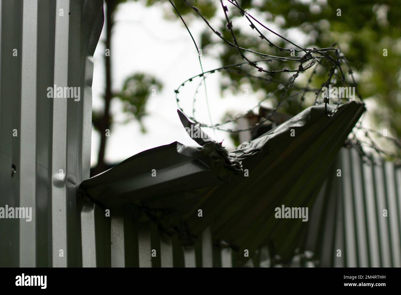 Broken fence. Steel fence crumpled. Damage to metal profile. Spoiled ...