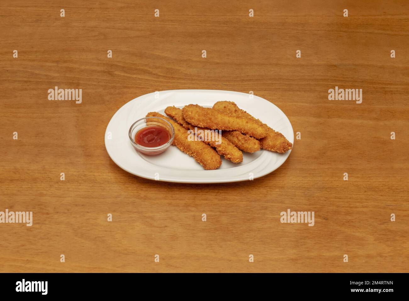 A serving of crispy chicken on a white porcelain tray with a glass bowl ...