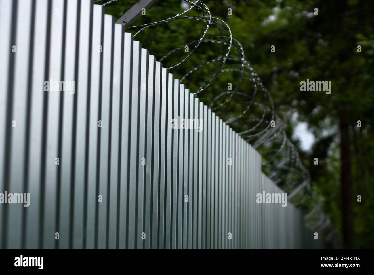 Steel fence with barbed wire. Fence around plant. Private territory ...