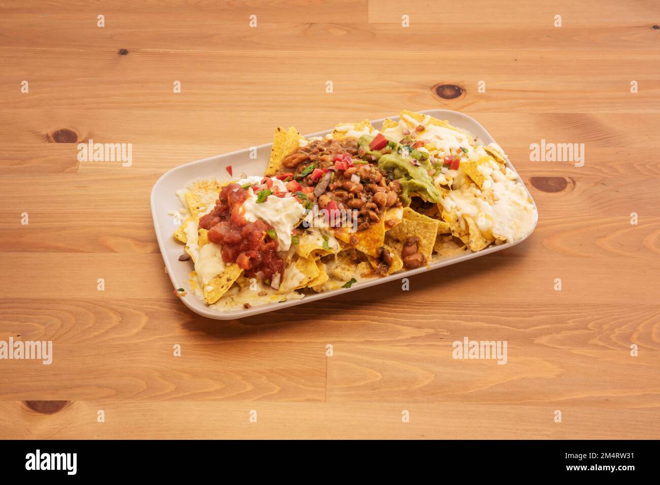A recipe tray of Mexican corn nachos with fresh cheese, guacamoles ...