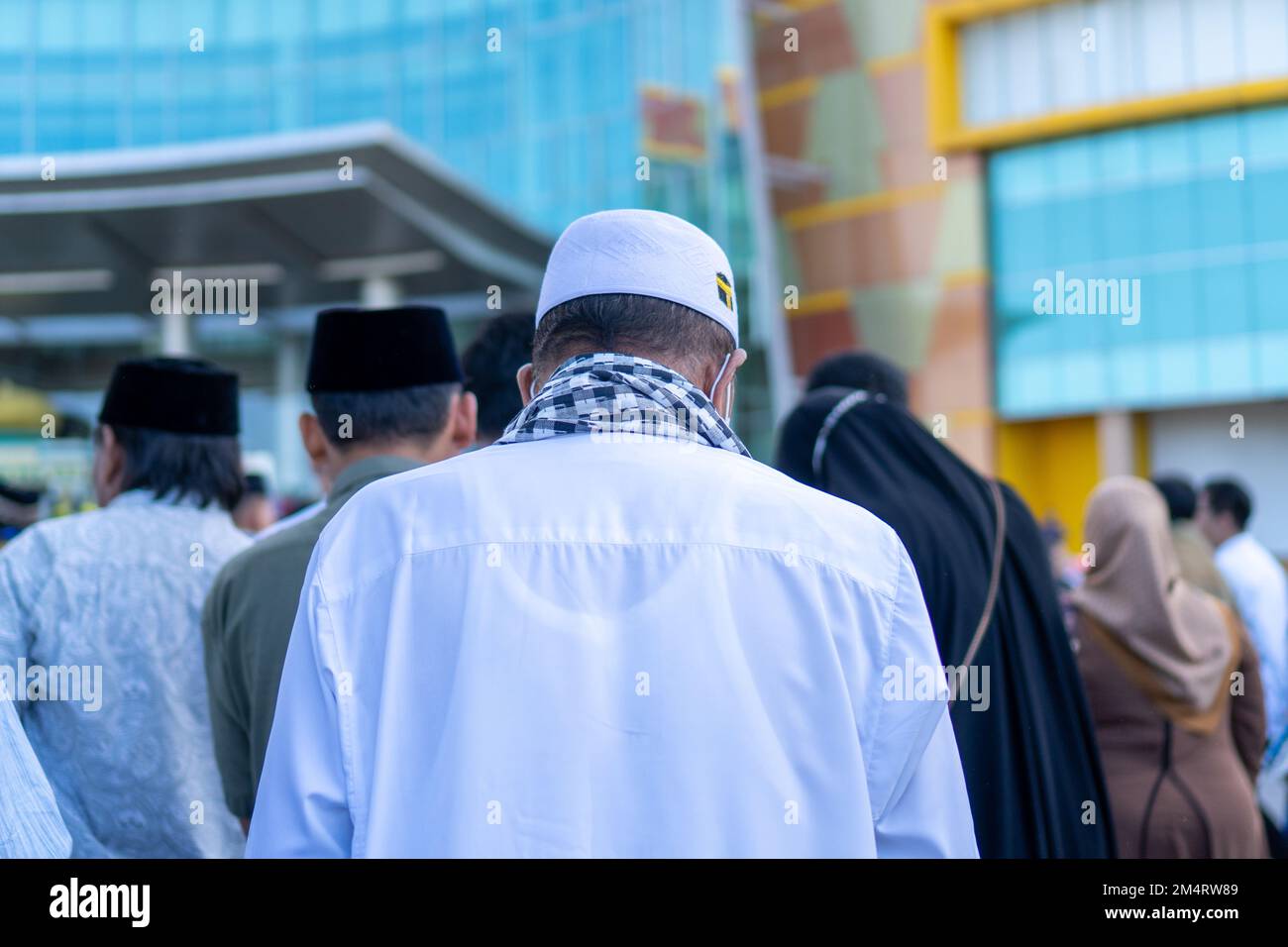 A Muslim man is walking among the crowd towards the mosque. Walk to the ...