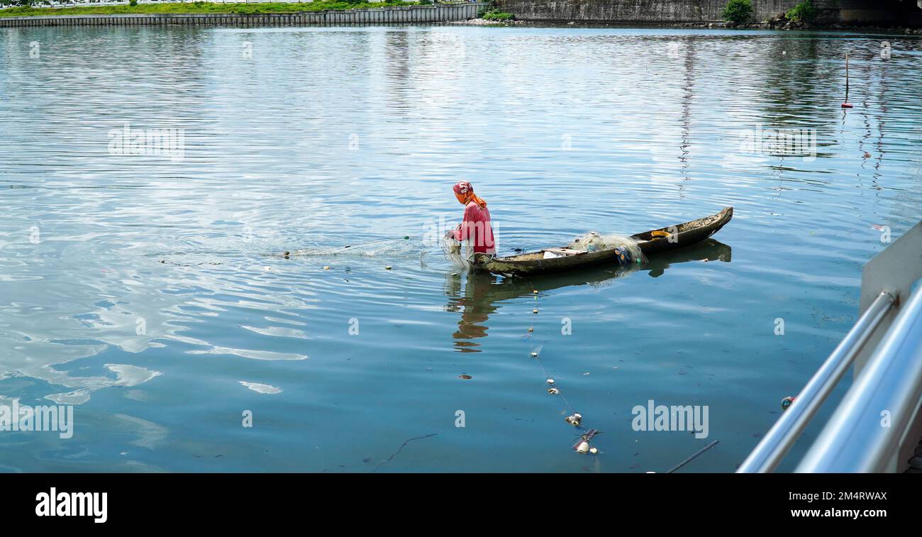 a traditional fisherman cleans trash on the beach using a net Stock ...