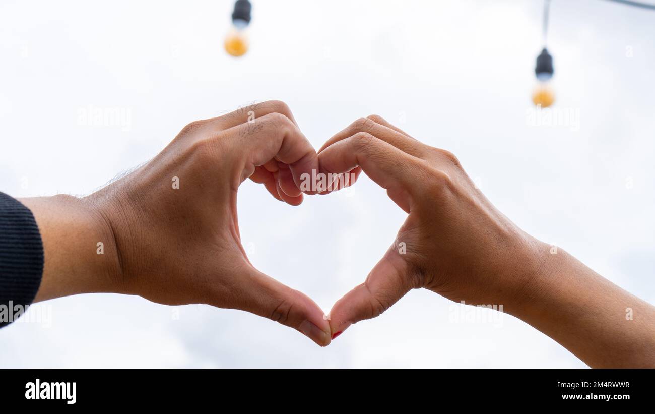 Heart symbol hand gesture on a cloudy and evening sky Stock Photo - Alamy