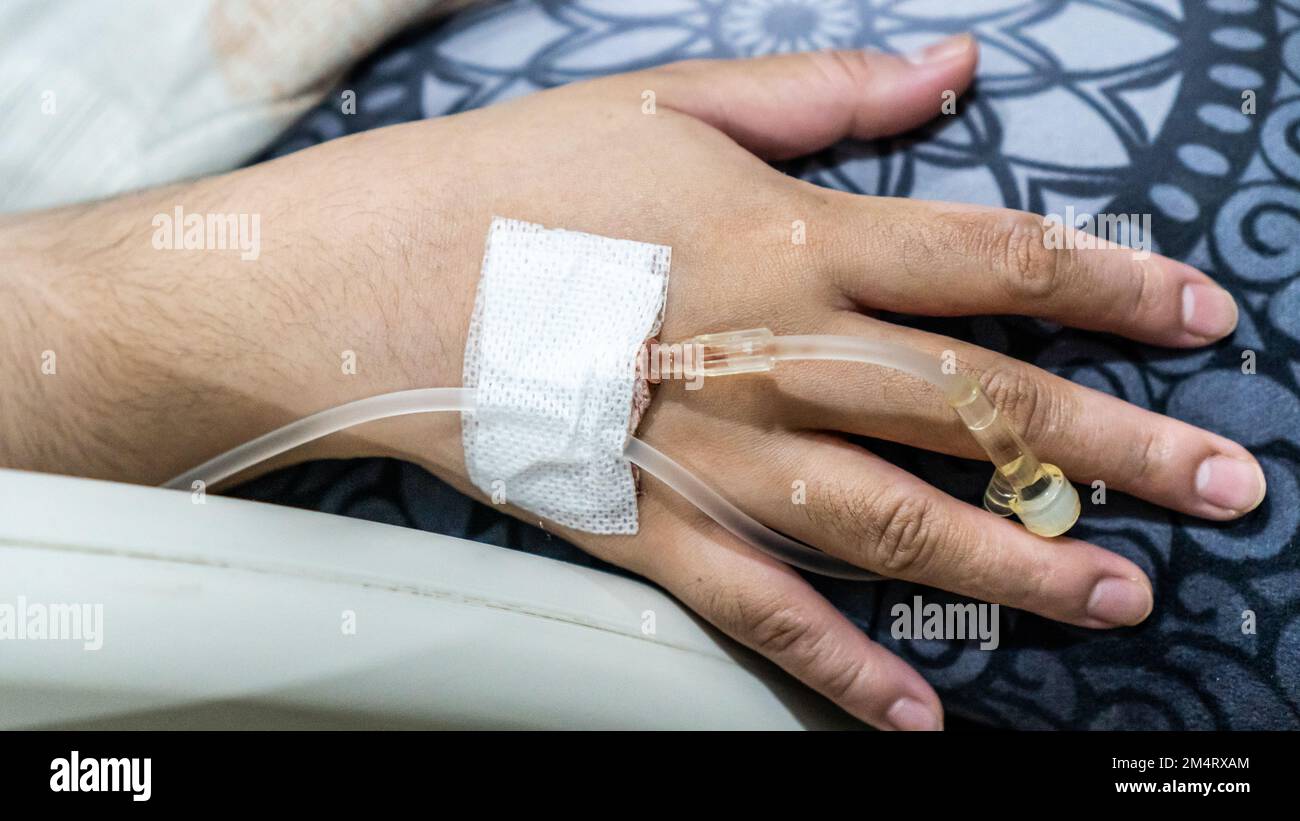 The hand of a female patient who is infused with saline in the hospital ...