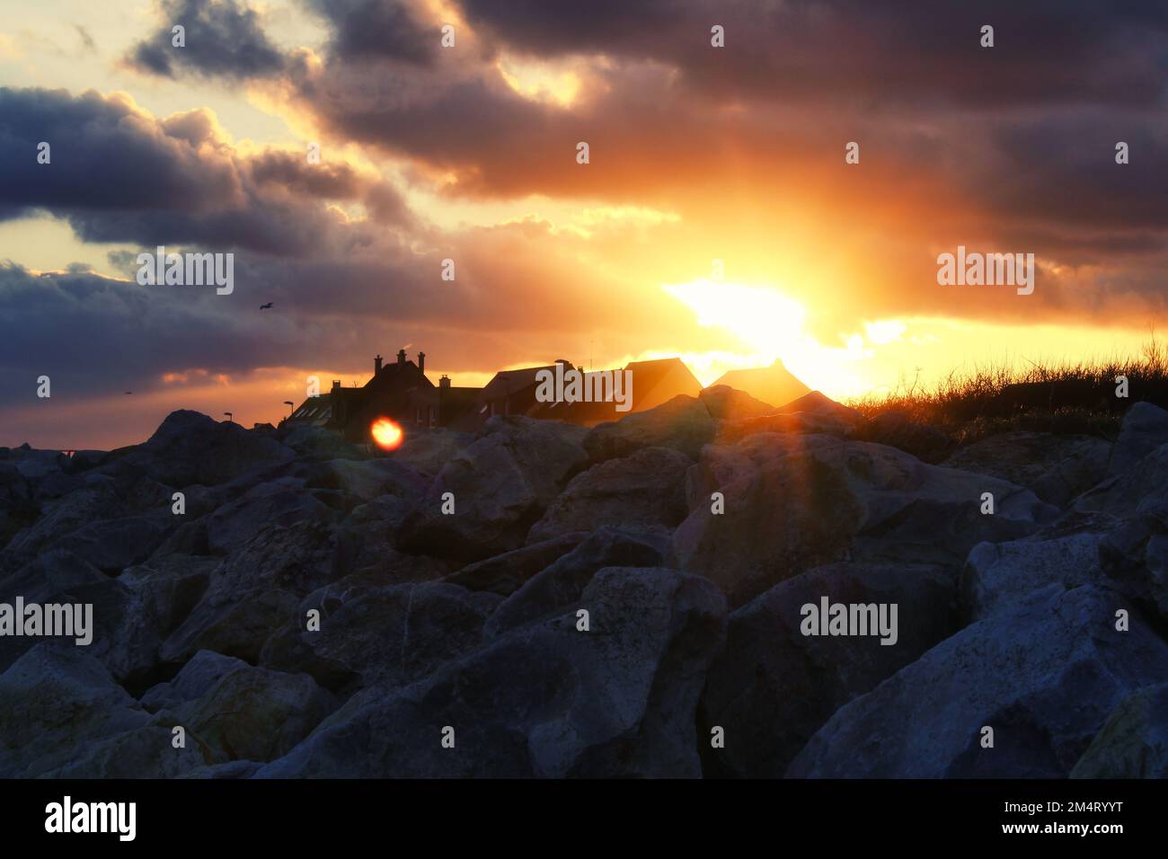 An aerial view of buildings behind rocks during sunset in Urville ...