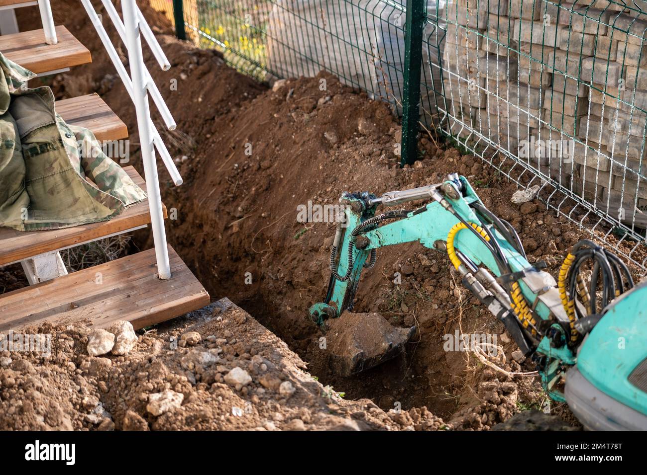 Mini excavator digs a trench to lay pipes. Close up of an excavator ...