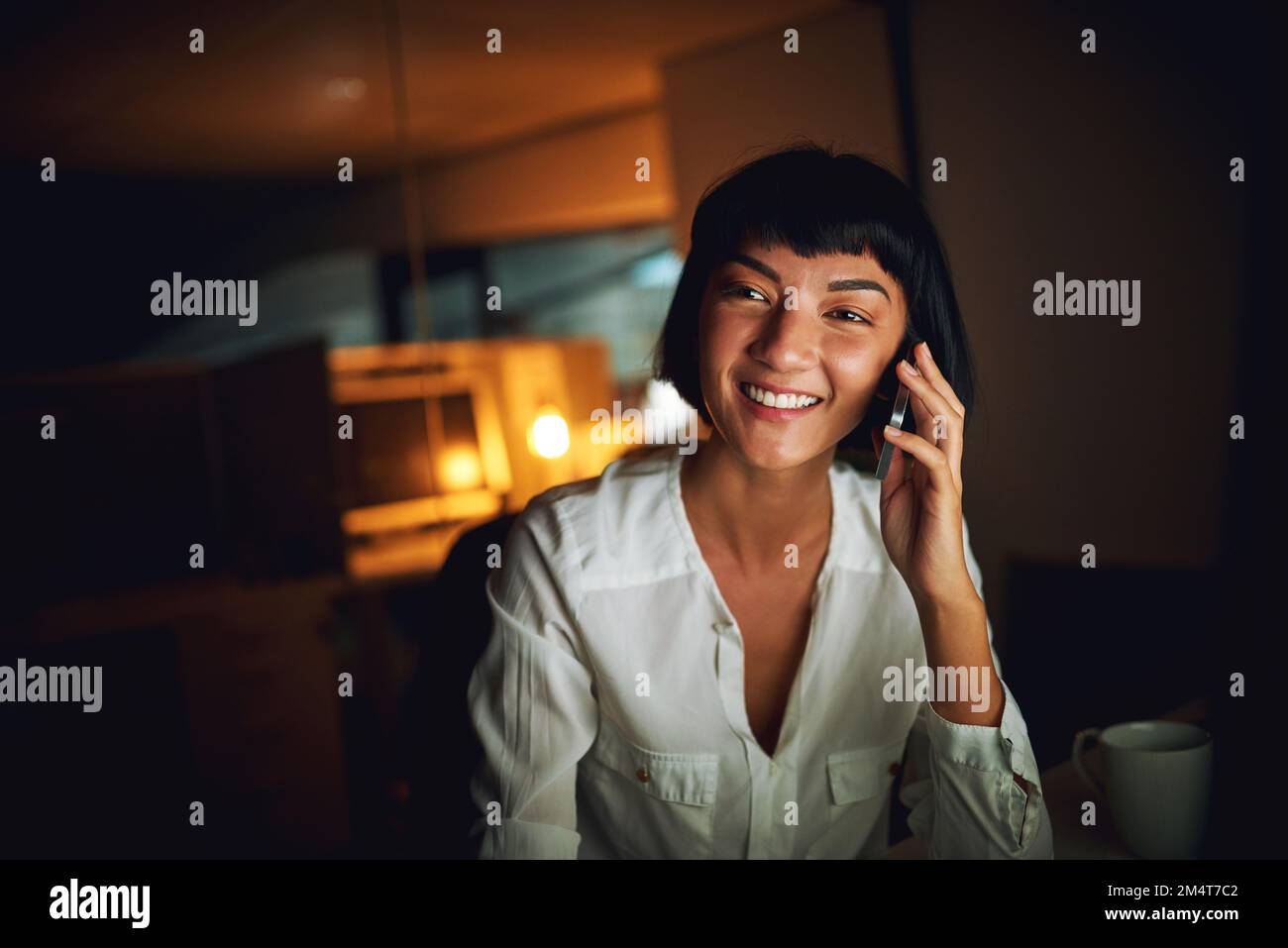 Im almost done with work. a young businesswoman using a mobile phone ...