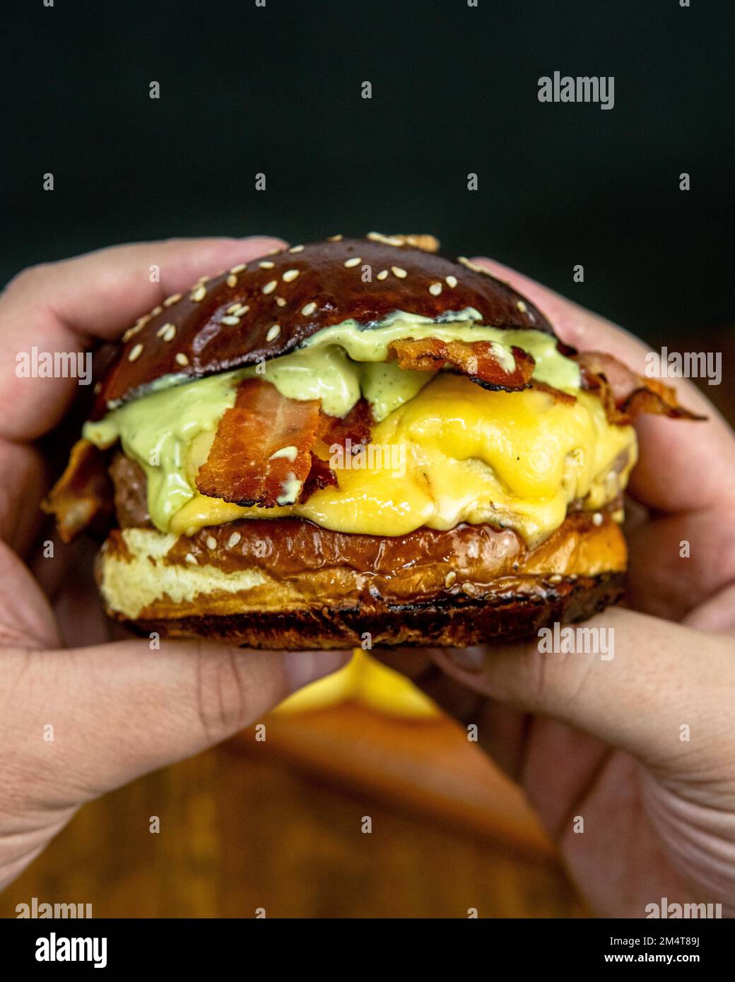 A vertical shot of juicy cheeseburger sandwich in human hands isolated ...