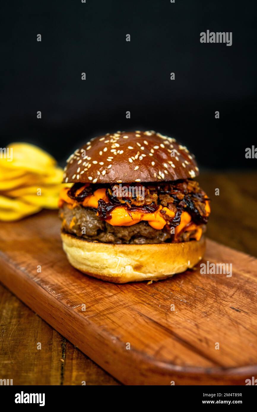 A vertical shot of cheeseburger sandwich with fried potatoes chips on ...