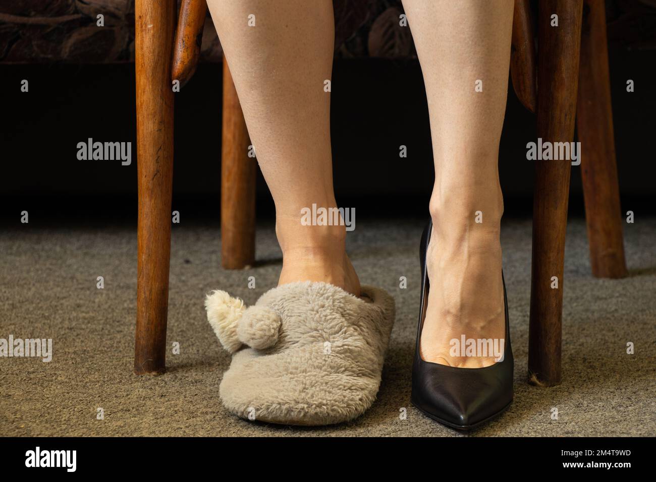 one foot in black high-heeled shoes and the other in indoor slippers on ...