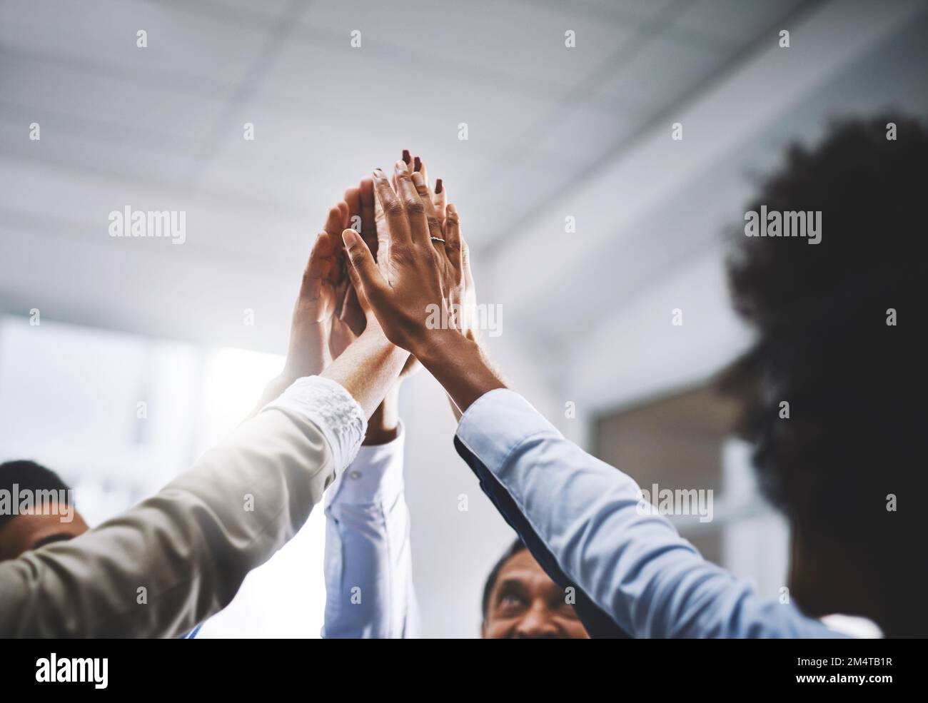 We work well together. a group of colleagues giving each other a high ...