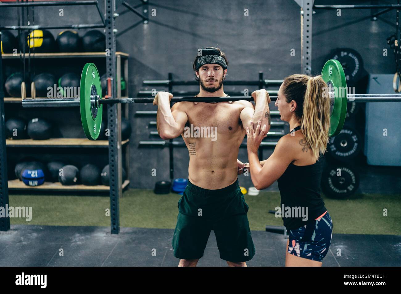 Female coach helping a man to lift weight in a gym Stock Photo - Alamy