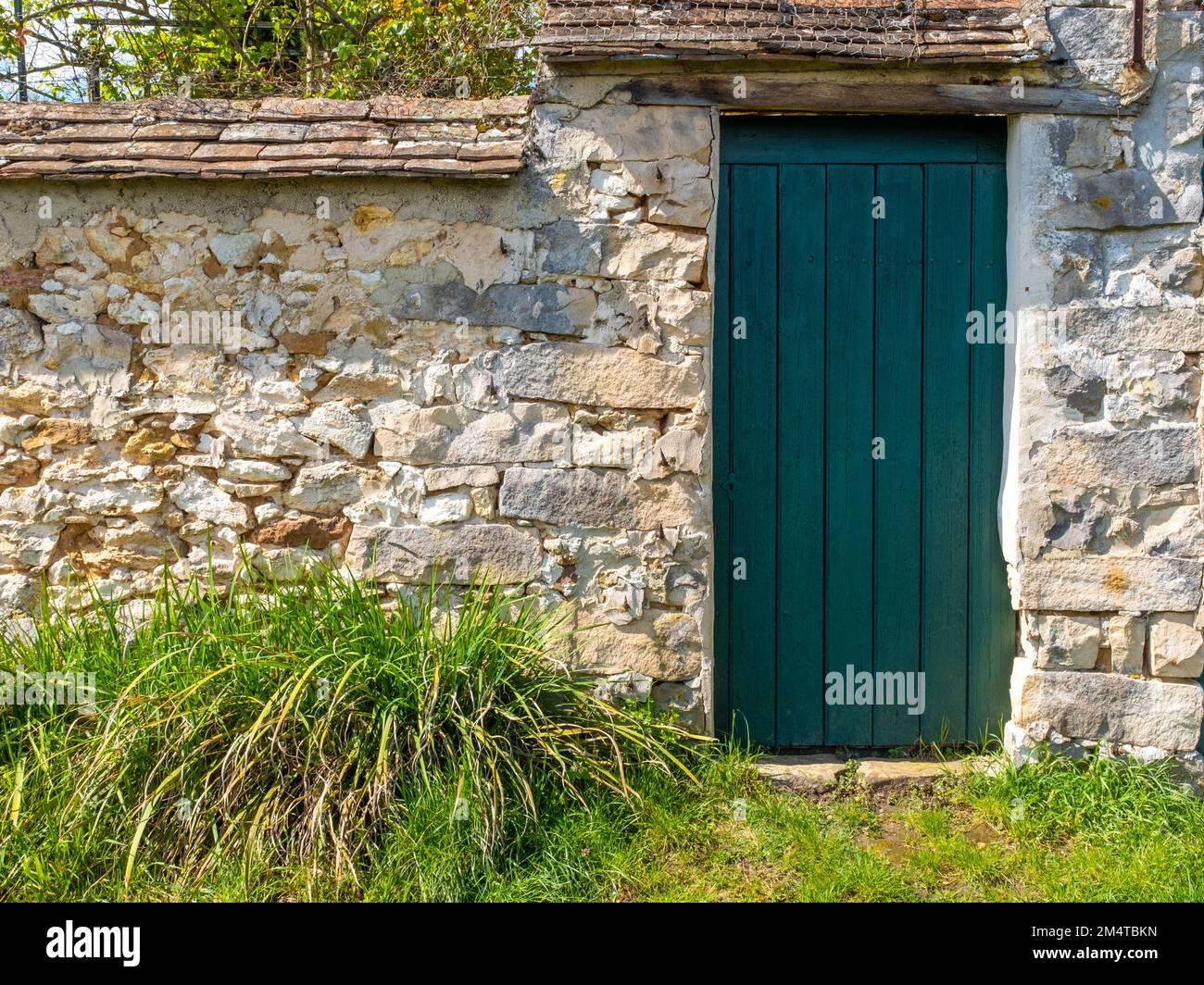 A green door in a limestone garden wall, taken in the town of Thomery ...
