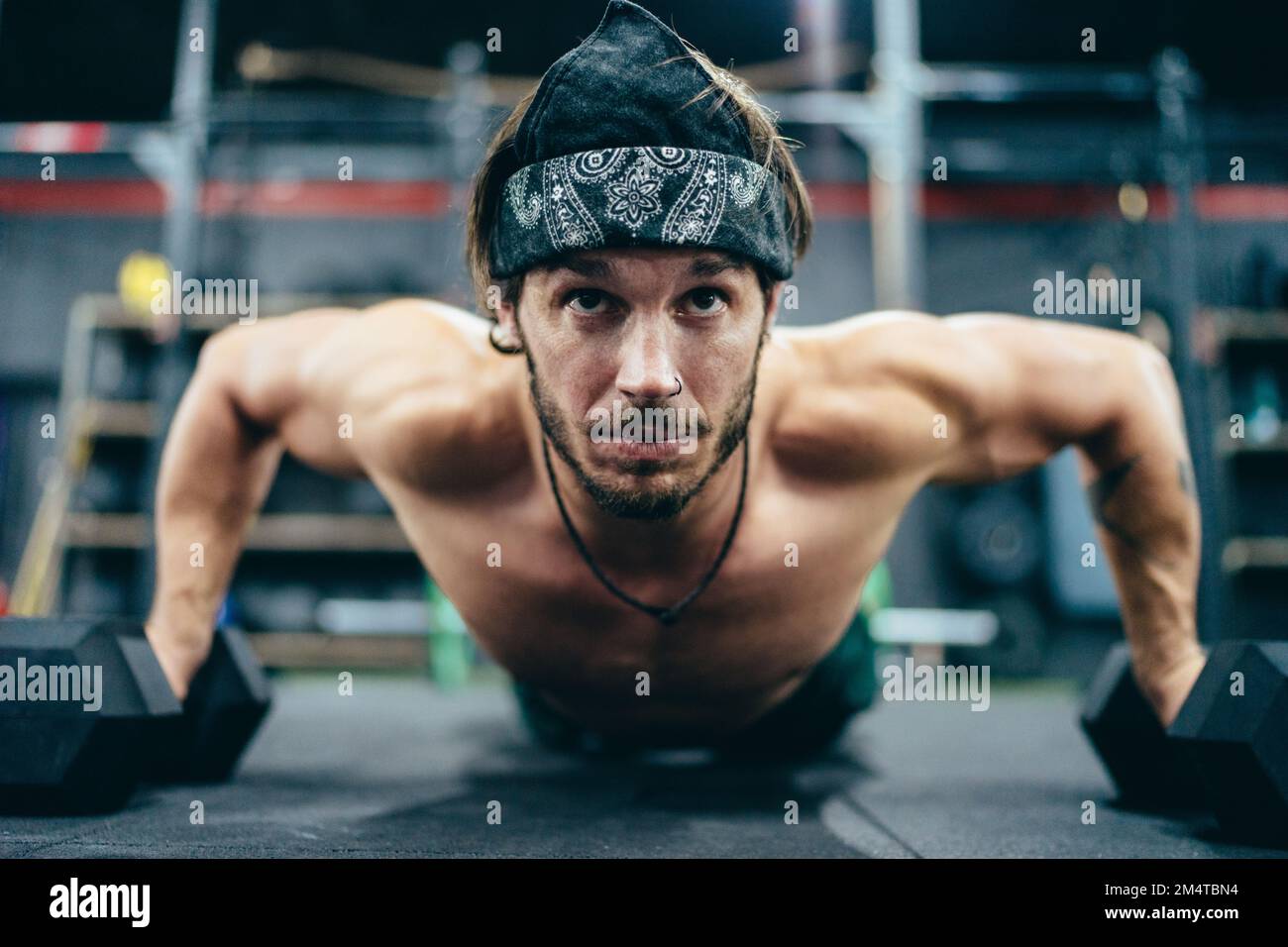 Close up photo of a fit handsome man doing push-ups using dumbbells in ...