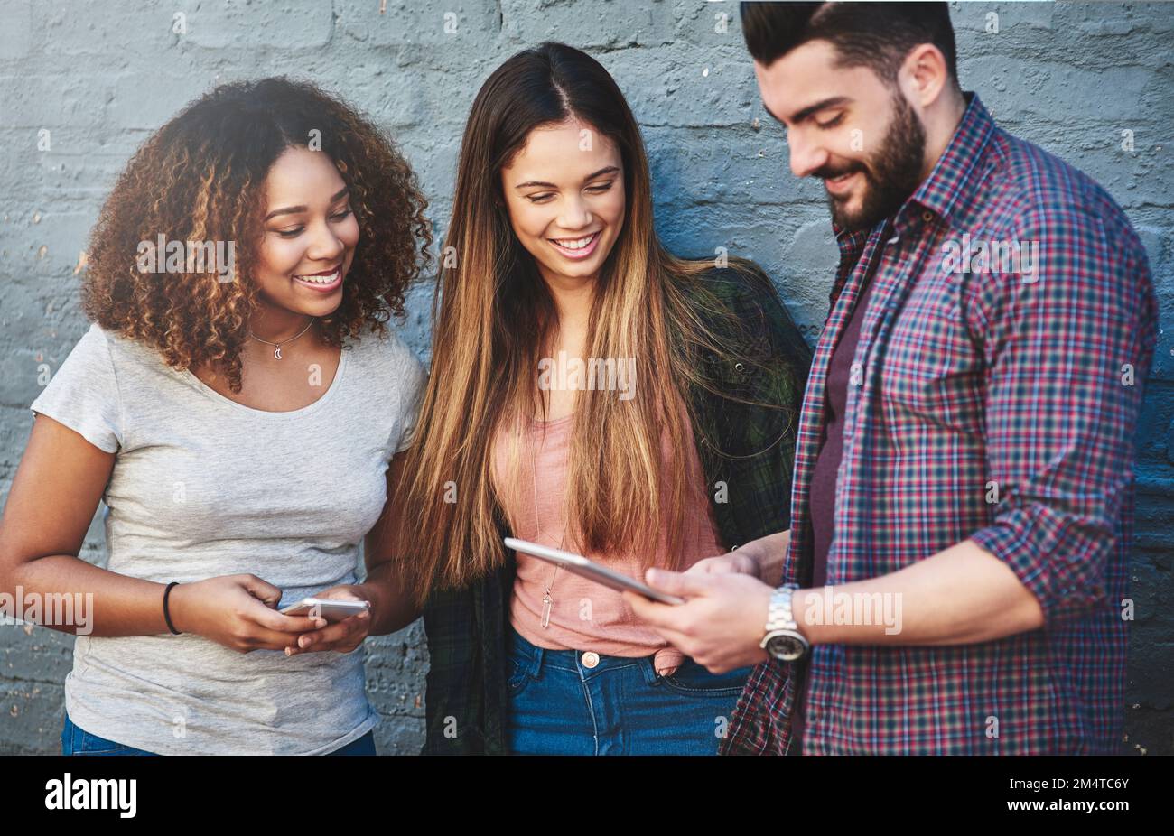 Sharing and connecting. a group of young friends using their wireless ...