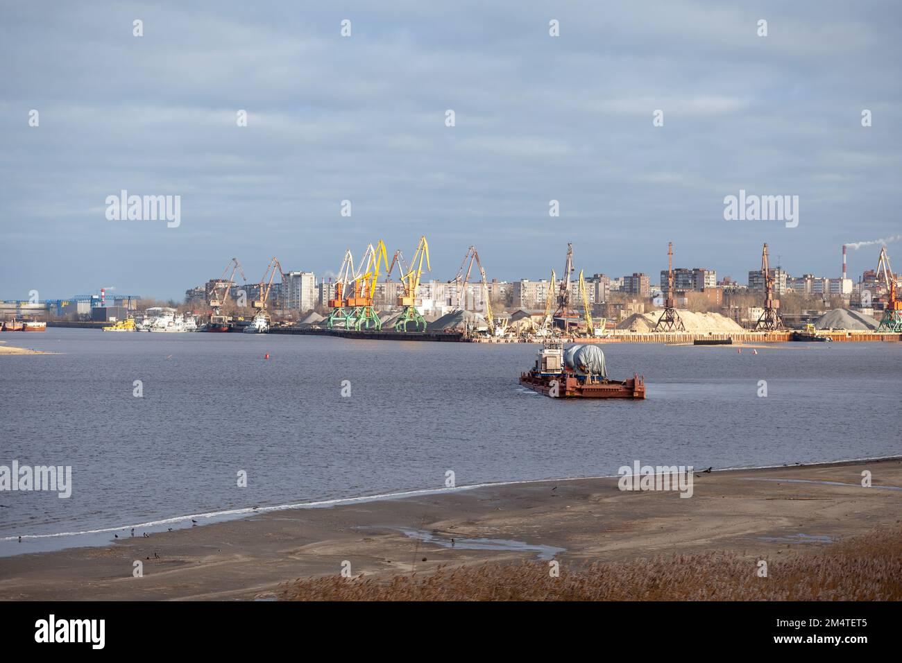 River port. Port cranes on the bank of the river. Embankment of the ...
