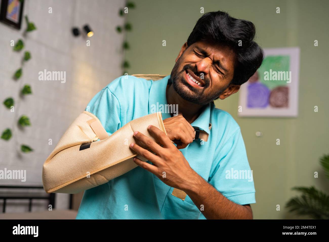 Medium shot of Young man suffering from broken or injured hand at home ...