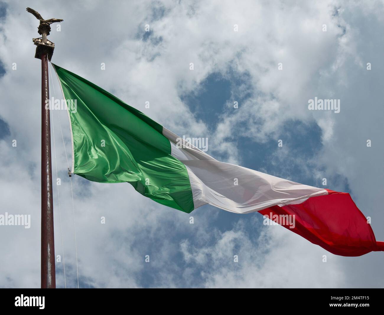 The Italian flag waving on a rusty metal flag pole with bird statue on ...