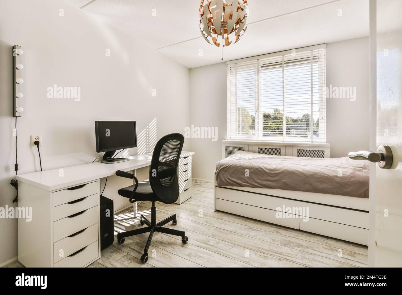 a bedroom with a bed, desk and computer monitor on the table in front ...