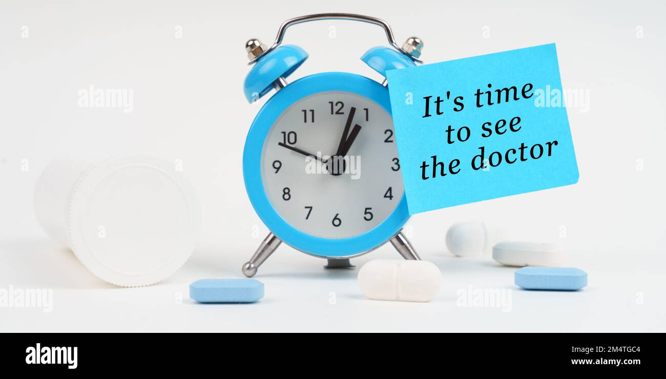 Medical concept. On a white surface there are pills and an alarm clock ...