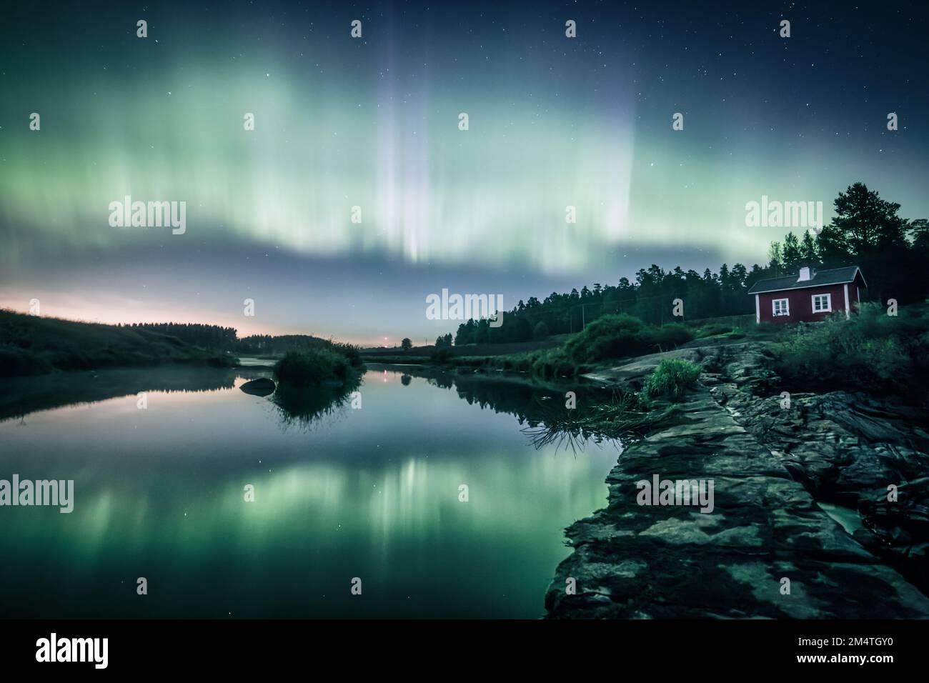 The polar Aurora lights in the starry sky over the small house near the ...