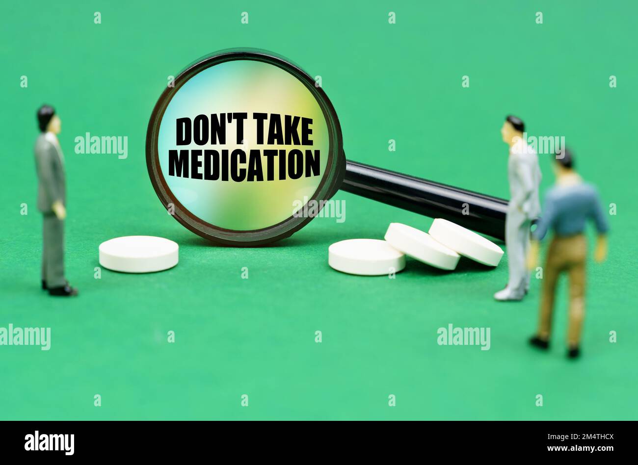 Medical concept. On a green surface are pills, miniature figures of ...
