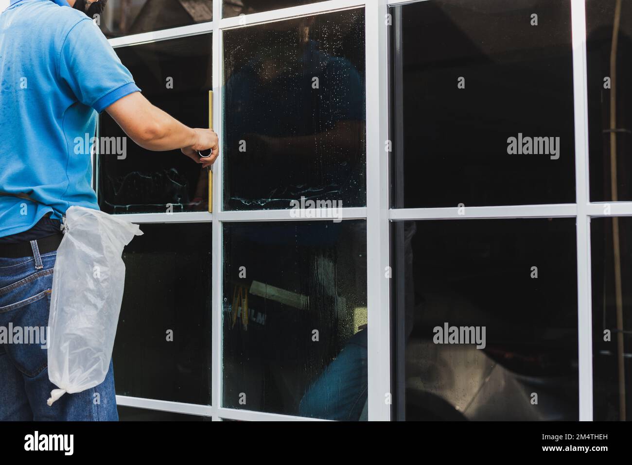 Worker use scraper cleaning window before installing tinting film Stock ...