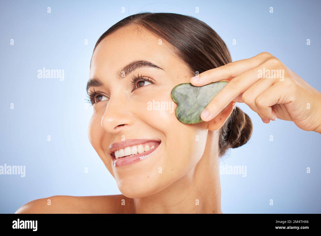 Skincare, beauty and woman with gua sha in studio on blue background ...