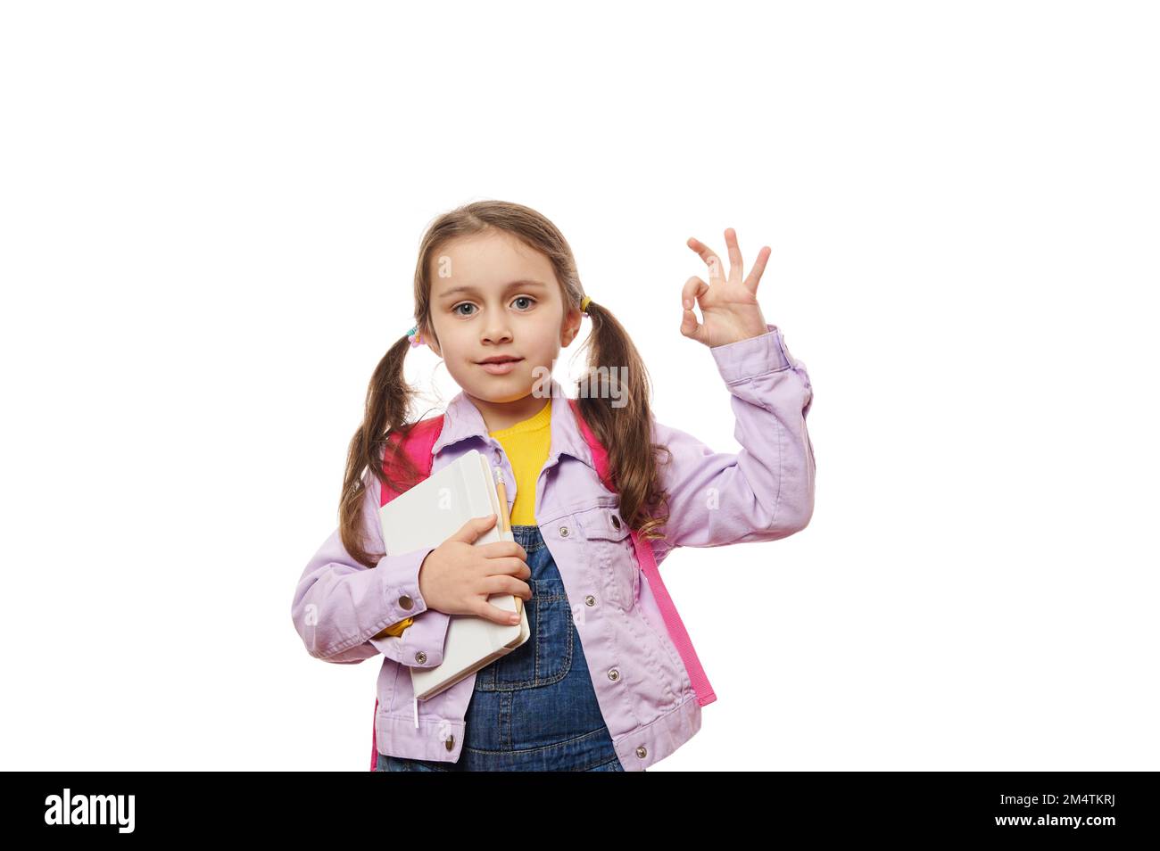Caucasian little girl shows OK sign, looking at camera. Happy school ...
