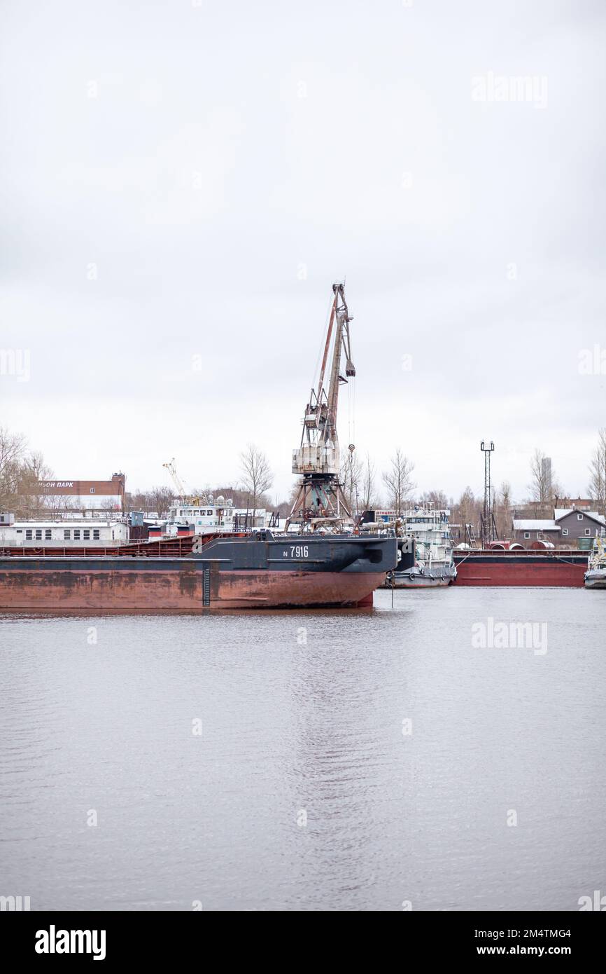 River port in winter. Port cranes on the bank of the river. Embankment ...