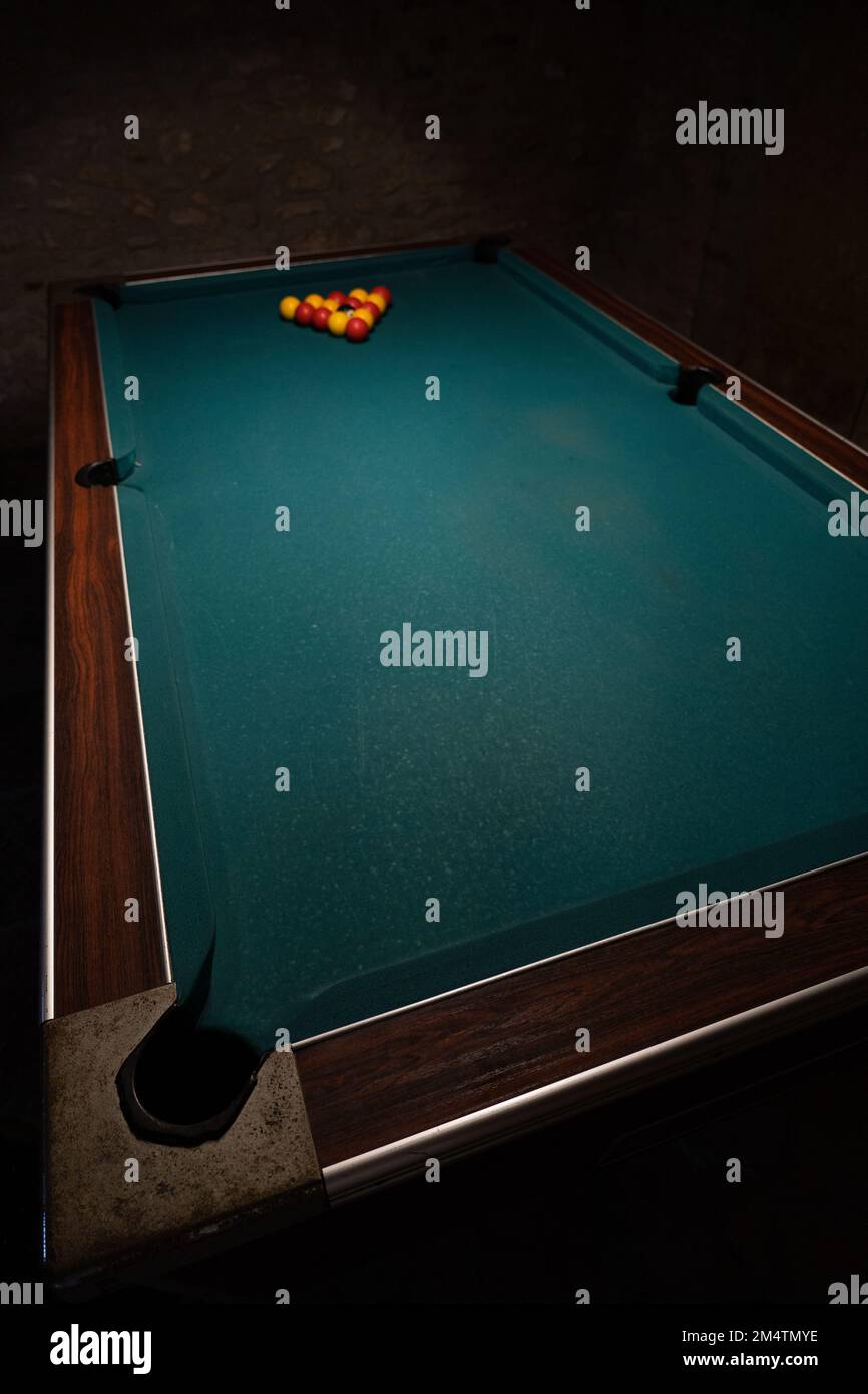 A vertical footage of a billiard table in a dark room with colorful ...