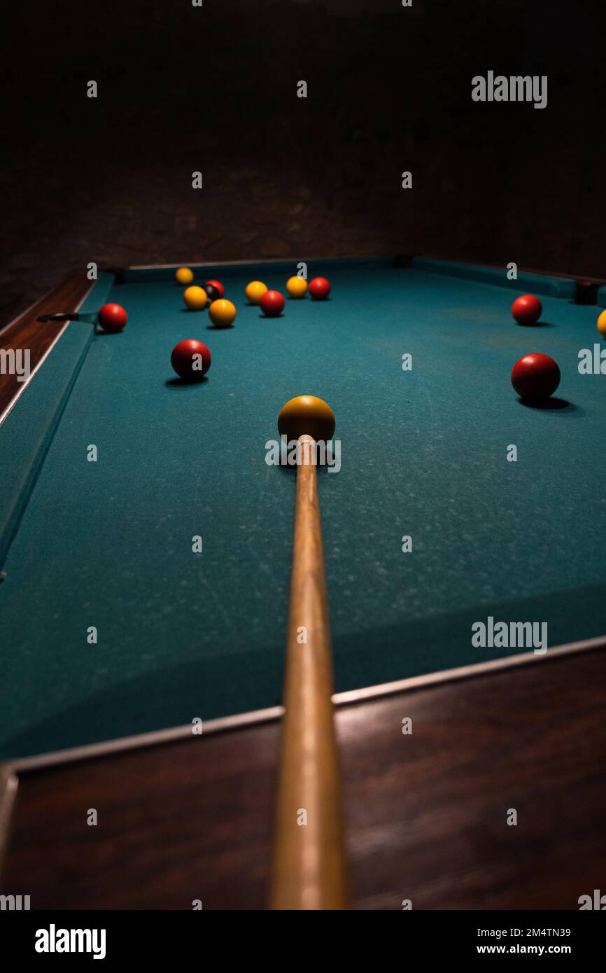 A vertical footage of a billiard table with balls and cue in a dark ...