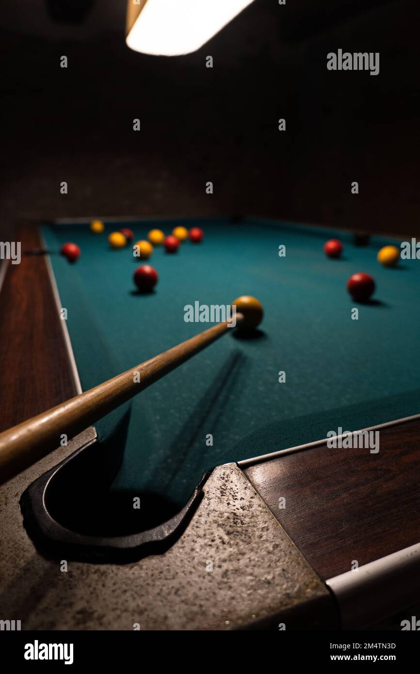 A vertical footage of a billiard table with balls and cue in a dark ...
