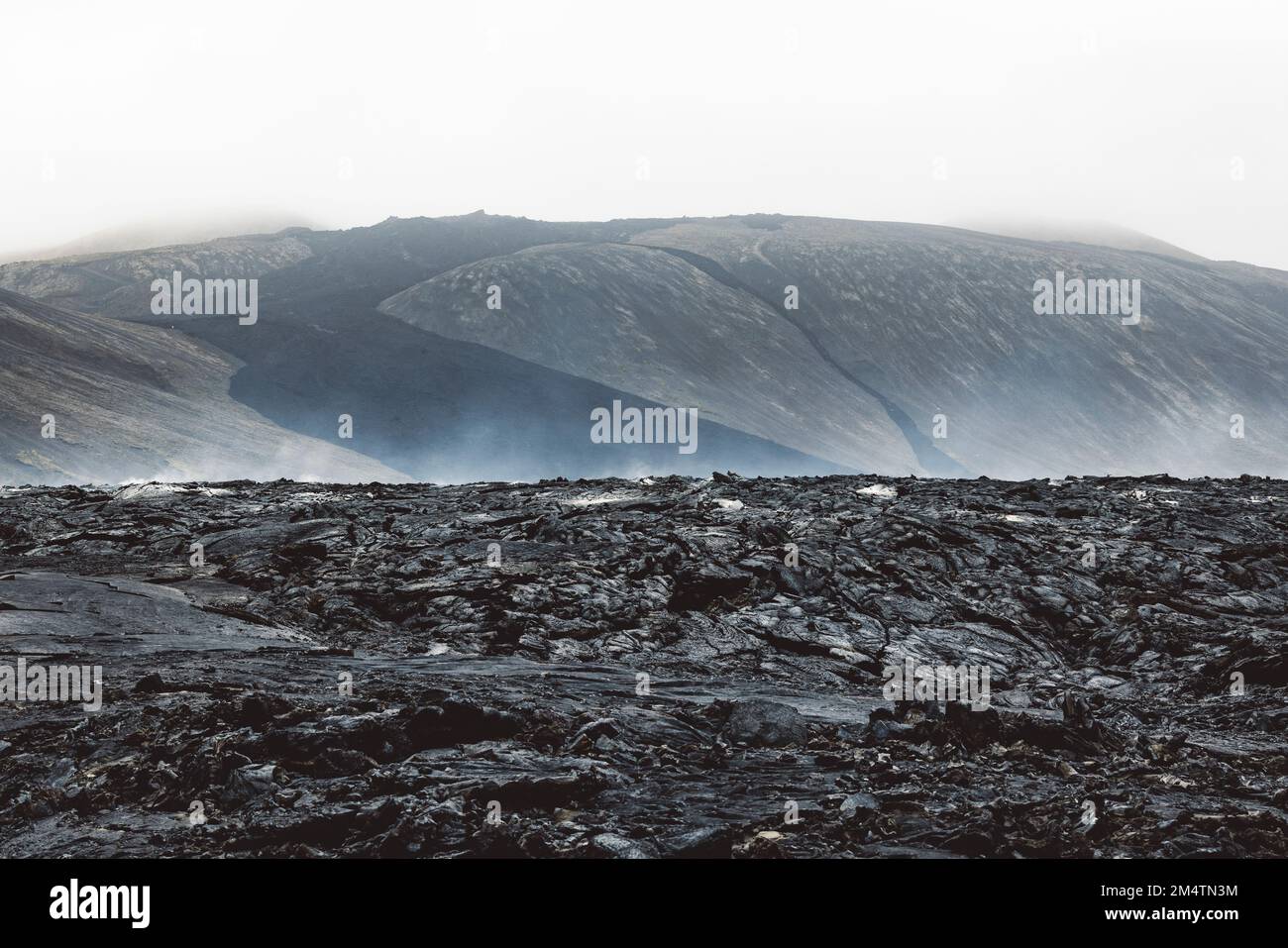 Dramatic view of still hot lava rocks and steam rising from the hot ...