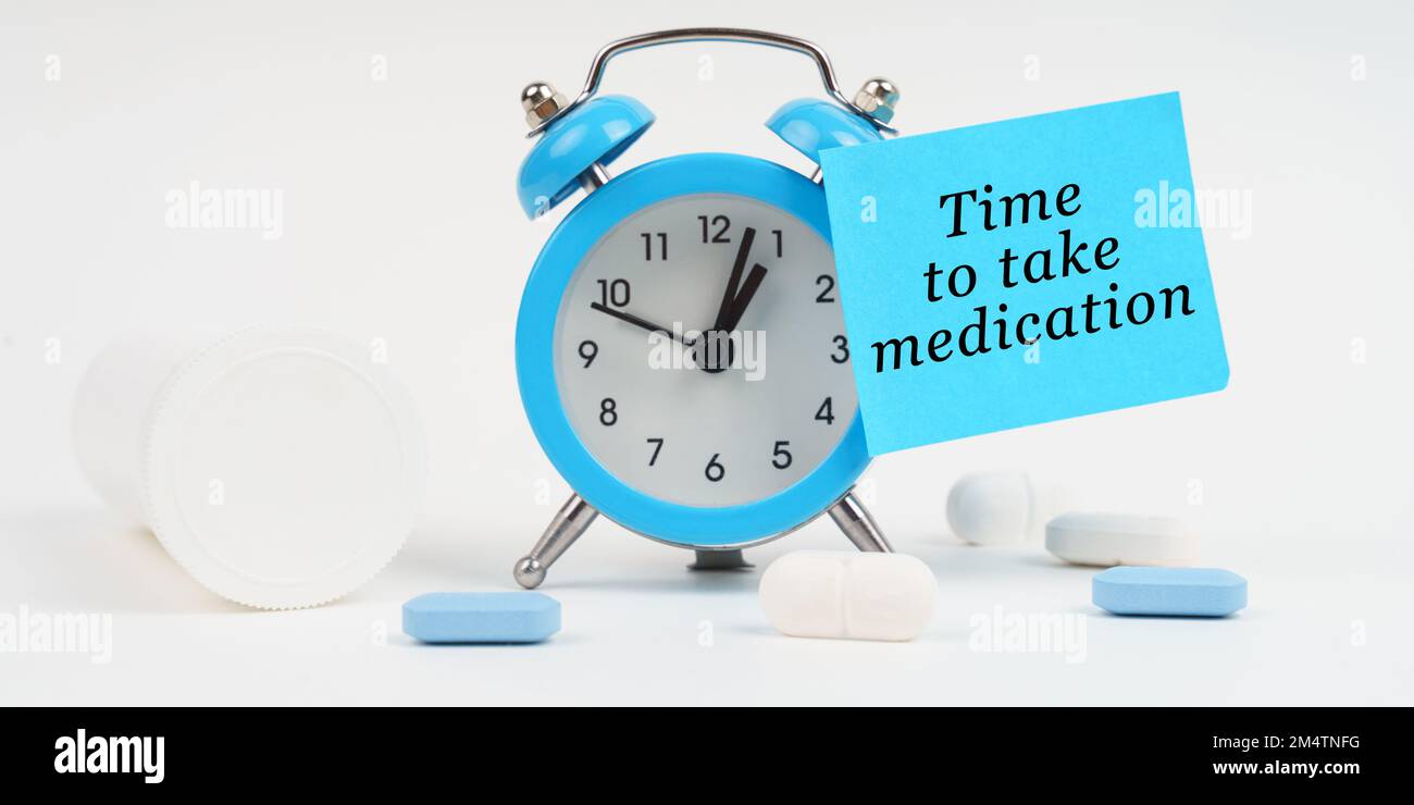 Medical concept. On a white surface there are pills and an alarm clock ...