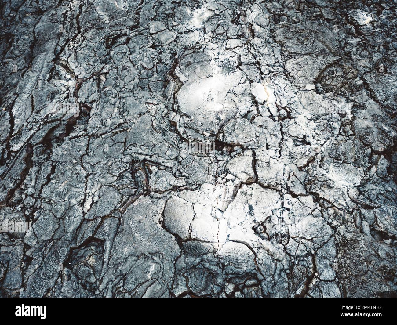 Ash grey sport on black volcanic rocks - Top down aerial view Stock ...