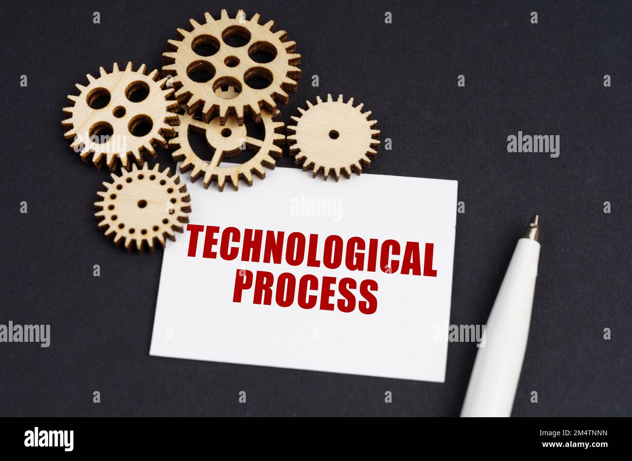 Industrial concept. On the black surface are gears, a pen and a business card with the ...